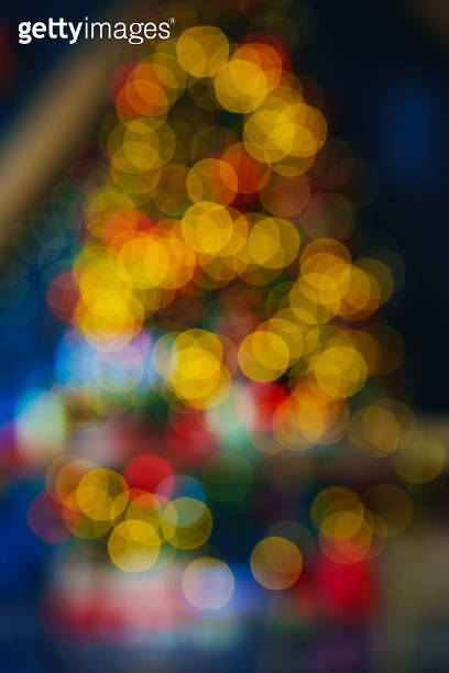 unfocused. a large Christmas tree decorated in a room with a black wall ...