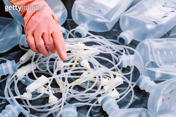 Hands of female officers sorting toxic waste, IV tubes, extension tubes ...
