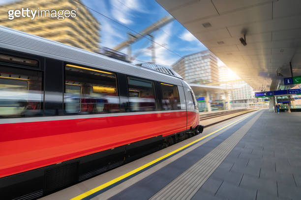Red high speed train in motion on the railway station at sunset. Fast ...