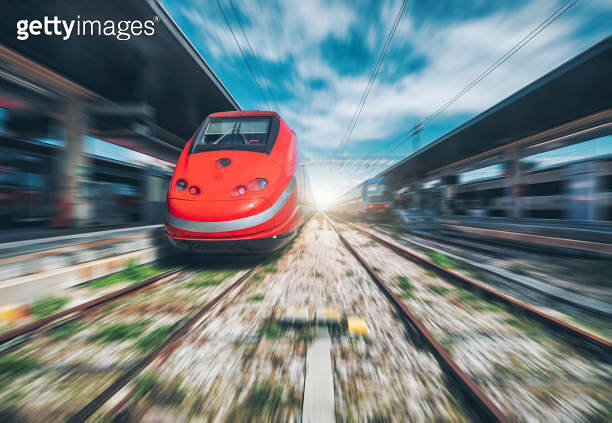 High speed train in motion on the railway station at sunset. Fast red ...