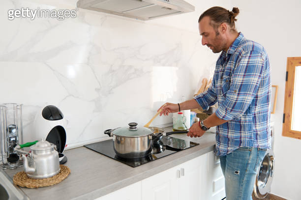 Handsome male chef enjoying a happy day-off at home, mixing ingredients ...