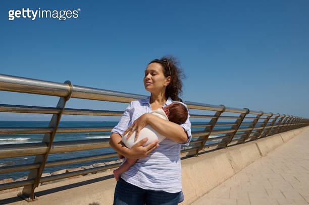 Loving mother carrying her newborn baby while walking along the ...