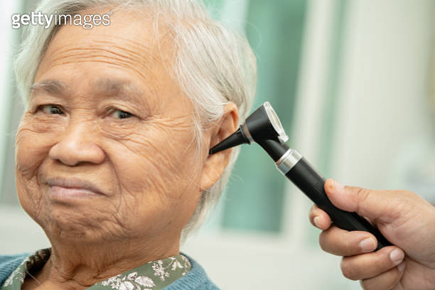Audiologist or ENT doctor use otoscope checking ear of asian senior ...