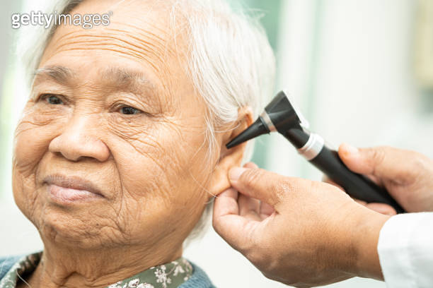 Audiologist or ENT doctor use otoscope checking ear of asian senior ...