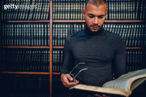 Smart male bookworm 30s making research in public library standing near ...