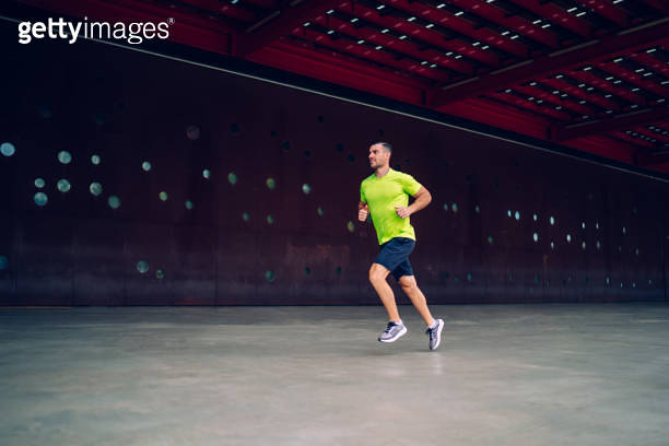 Side view of determined male runner sprinting during cardio training at ...