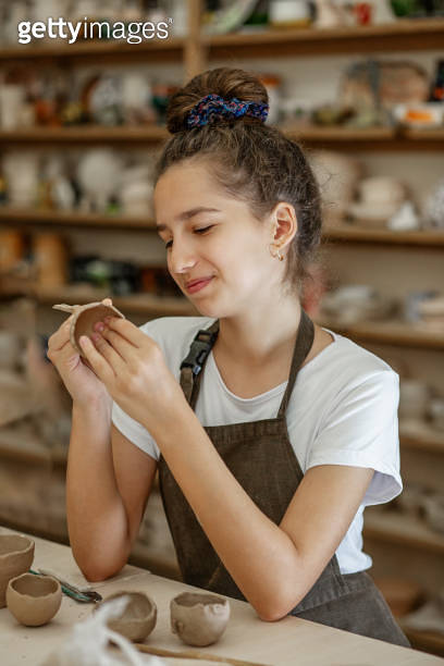 Beautiful teenage girl playing with modeling clay in pottery workshop ...