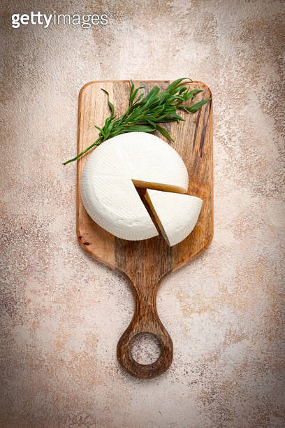 Head of Georgian cheese, Imereti variety, top view, on a cutting board ...