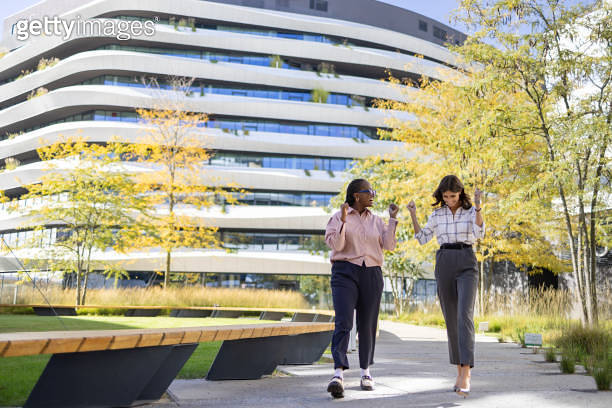 Cheerful female colleagues celebrating their success on the move in the ...