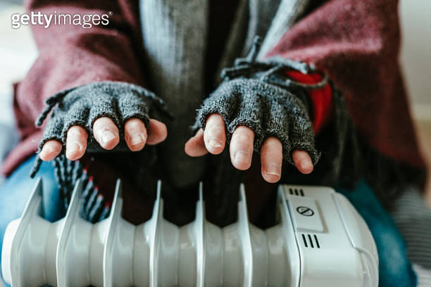 Cold senior man warming his hands over electric heater at home 이미지 ...
