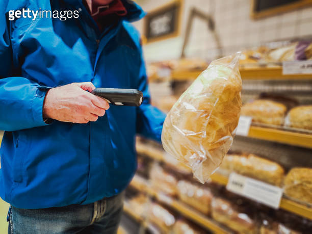 Man holding bar code scanner and scanning loaf of bread in store 이미지 ...