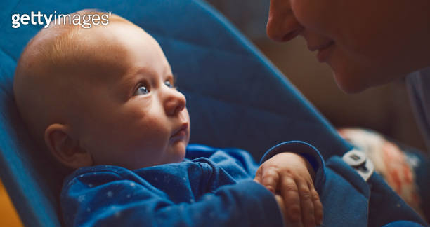 Adorable Curious Baby Boy Staring Mother While Relaxing In Bouncer At ...