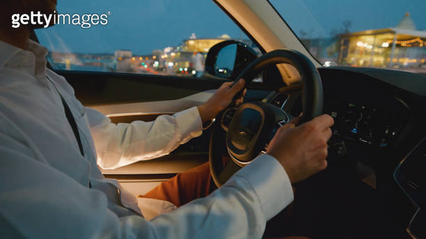 Young man driving car in illuminated city during blue hour 이미지 ...