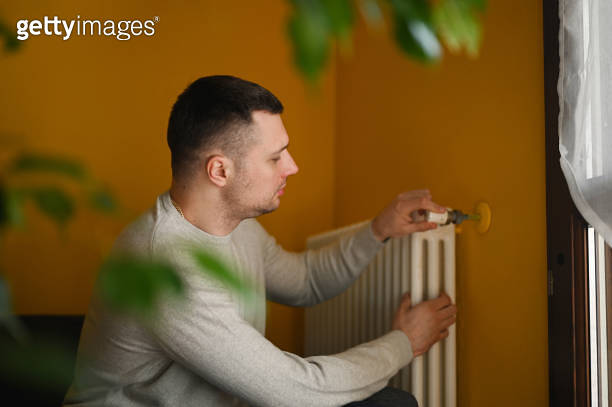 Mid adult man checking radiator at home. 이미지 (1794642554) - 게티이미지뱅크