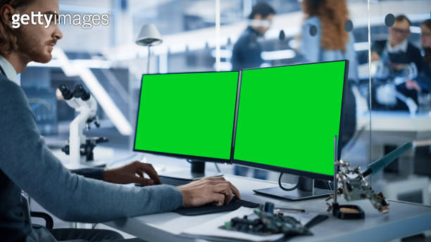 Software Developer Working on Computer with Green Screen Mock Up Display. Scientific Lab ...