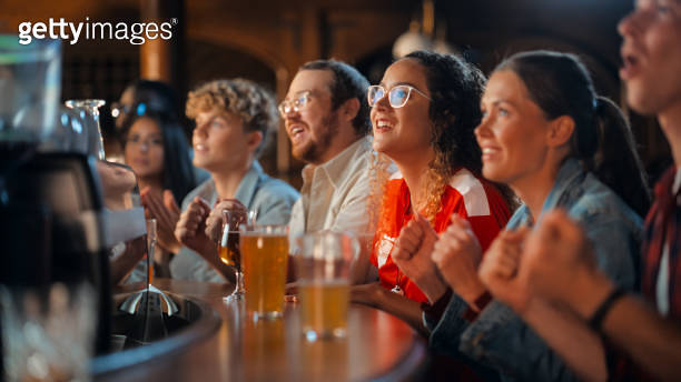 Group of Soccer Fans Sitting at a Bar Counter, Drinking, Watching a ...