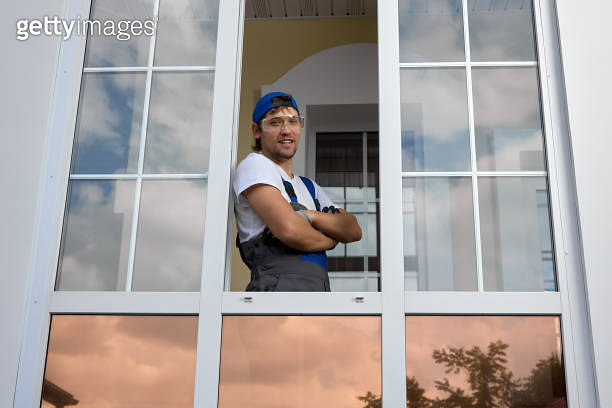 Portrait young worker in work uniform and blue cap standing with smile ...
