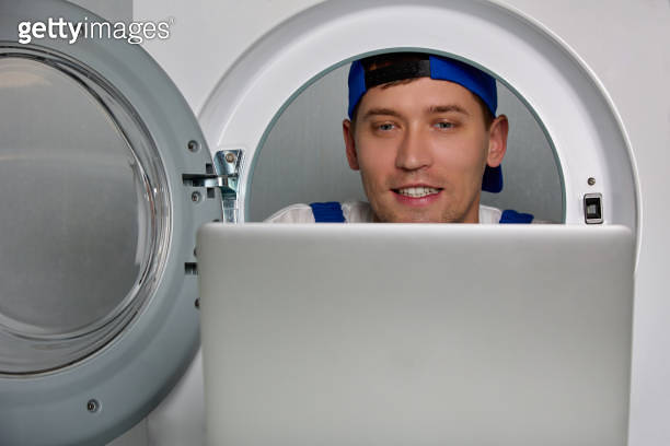 Master looks laptop screen through open hole for loading laundry ...