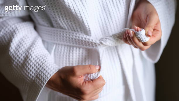 Natural fabric and closeup of female hands tying belt of white robe 이미지 ...
