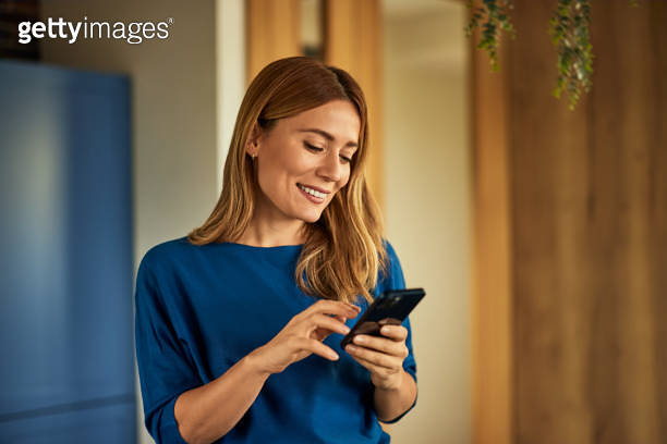 Side view of a smiling woman, chatting with someone over the mobile ...