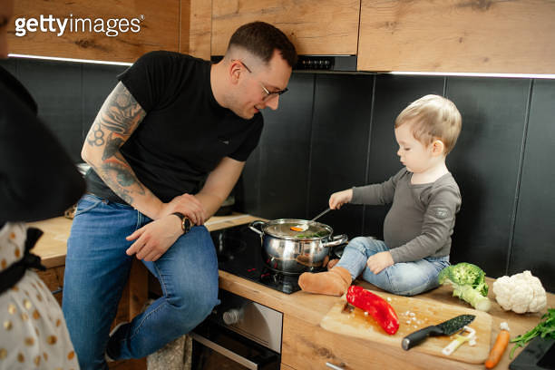 Portrait of family of little boy, young man cooking in kitchen. Toddler ...
