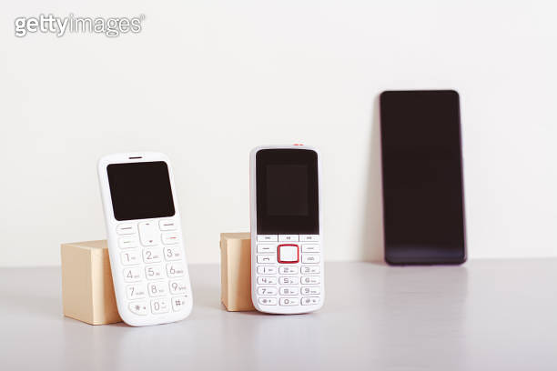 Two old-fashioned white push-button phones are on the table and a ...