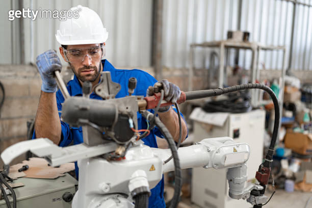 Caucasian engineer man repair arm robot with wrench at robot factory ...