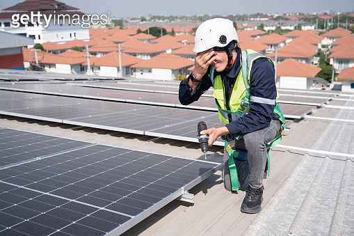 Tired Caucasian engineer man dizzy of working with solar panel on roof ...