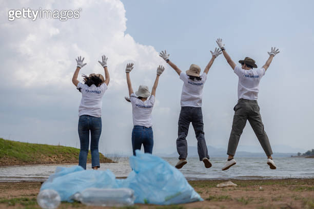 Group of volunteers cheerful success jumping together and arms raised ...