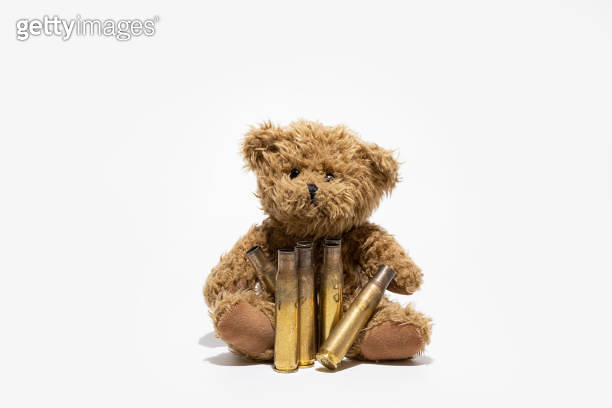 Empty machine gun cartridges and a brown teddy bear on a white ...