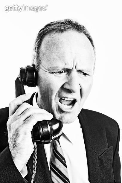 Angry businessman or old-school journalist talking on an old-fashioned ...