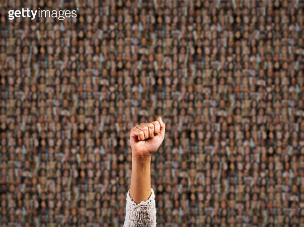 Fighting for humanity: woman's clenched fist rises in front of a group ...