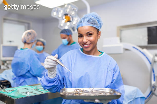 Female surgeon in surgical uniform taking surgical instruments at ...