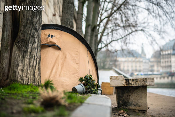 Homeless man in a tent near the wall on the river bank in Paris France ...