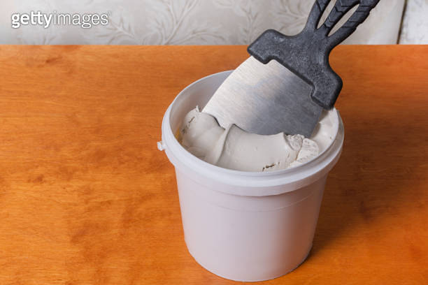 White putty in a plastic box ready to repair the old wall. Construction ...