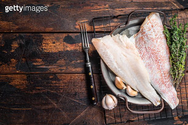 Raw red perch fillet, redfish fish meat in a steel tray. Wooden ...