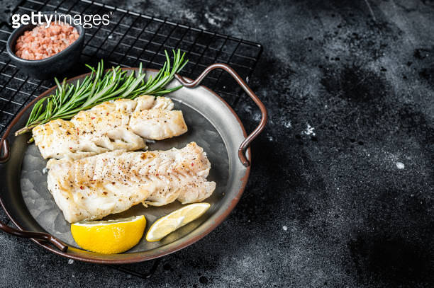 Roast Fillets of codfish, cooked cod fish meat. Black background. Top ...