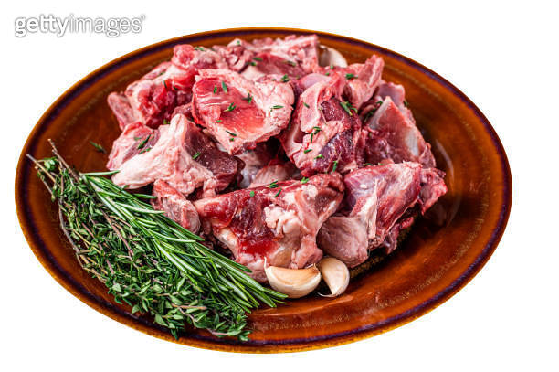 Raw mutton meat diced for goulash or stew with bone on a rustic plate ...