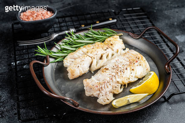 Roast Fillets of codfish, cooked cod fish meat. Black background. Top ...