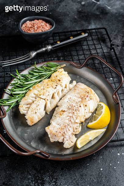 Roast Fillets of codfish, cooked cod fish meat. Black background. Top ...