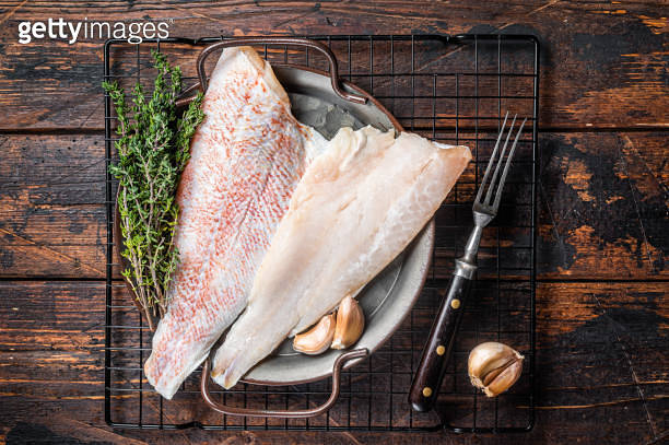 Raw red perch fillet, redfish fish meat in a steel tray. Wooden ...