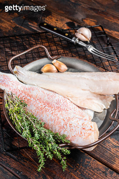 Raw red perch fillet, redfish fish meat in a steel tray. Wooden ...