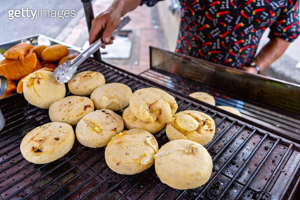 Man grilling Colombian arepas at a traditional stall in the streets of ...
