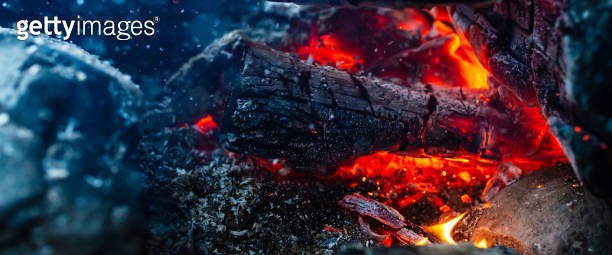 Smoldered logs burned in vivid fire. Atmospheric background with orange ...