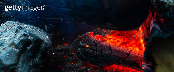 Smoldered logs burned in vivid fire. Atmospheric background with orange ...