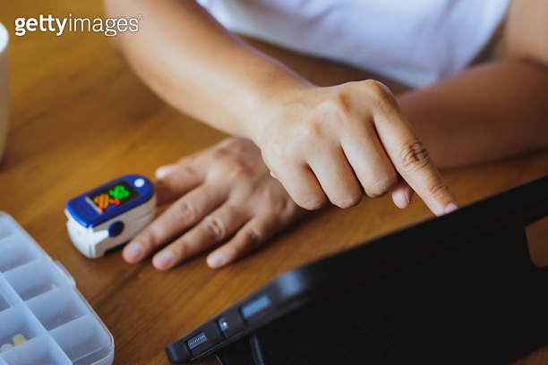 Asian woman self testing for blood oxygen levels with pulse oximeter ...