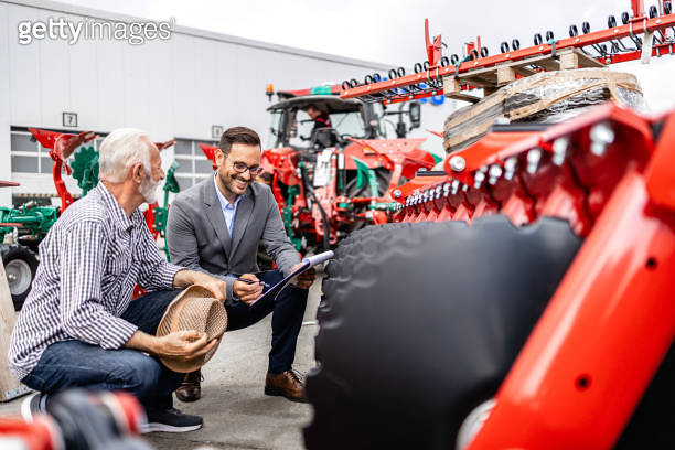 Farmer and tractor dealer discussing about harrow and farming equipment ...