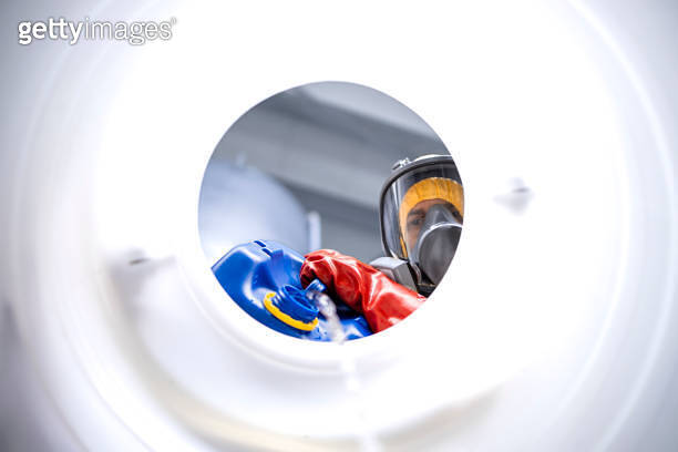 Inside barrel view of factory worker with gas mask and gloves mixing ...