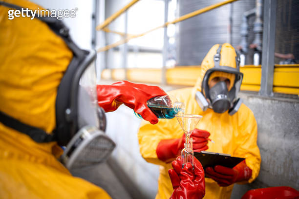 Chemical factory workers in protection suit and gas masks taking ...