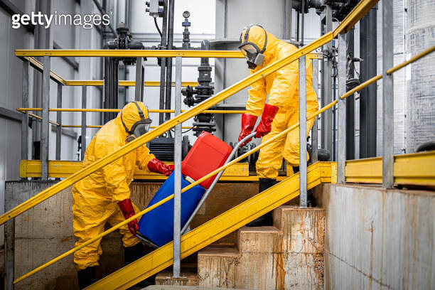 Workers in yellow protection suits and respiratory full face masks ...